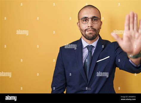 Hispanic Man With Beard Wearing Suit And Tie Doing Stop Sing With Palm