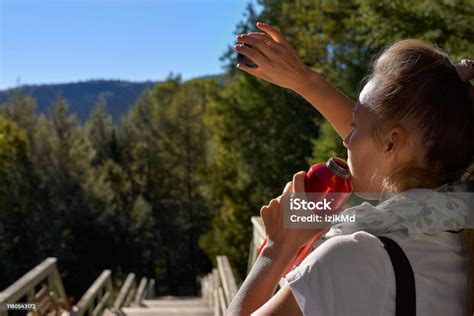 화창한 여름 날에 산에 서 병에서 물을 마시는 흰색 티셔츠에 매력적인 젊은 금발 보정 밝은 색상 T 셔츠에 대한 스톡 사진 및