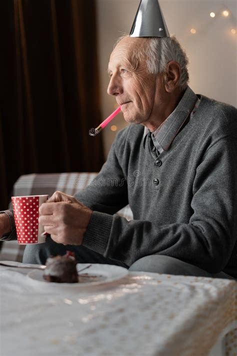 Unhappy Retired Man Wearing Cone Hat With Horn In Mouth Looking Away