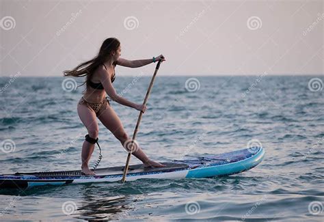 Girl On A Sup Board In The Sea With A Paddle Professionally Swims Beautifully And Gracefully