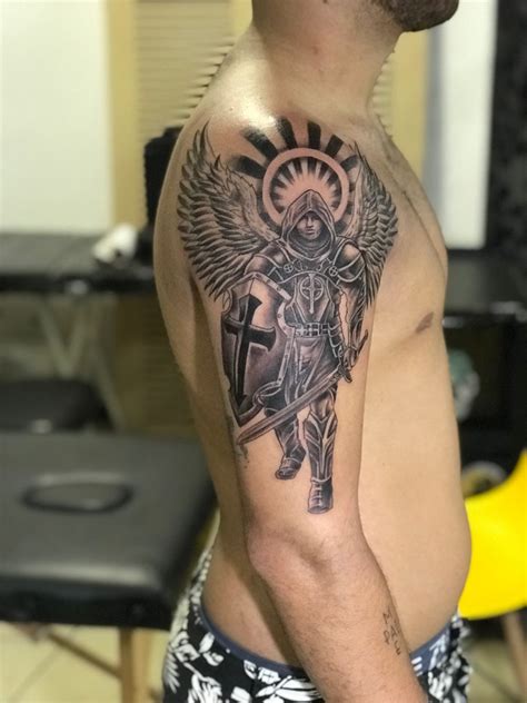 A Man With A Cross And Angel Tattoo On His Chest