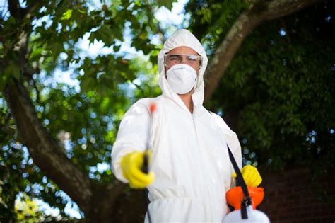 Premium Photo Man Spraying Insecticide While Standing Against Tree