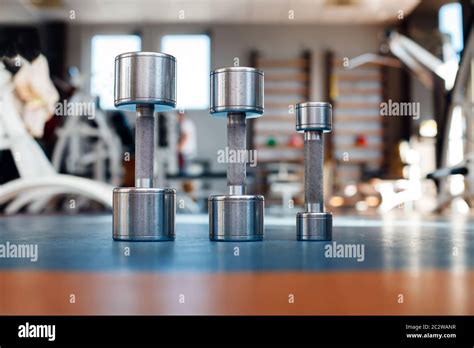 Three Dumb Bells Of Different Size On The Floor In The Gym Focused