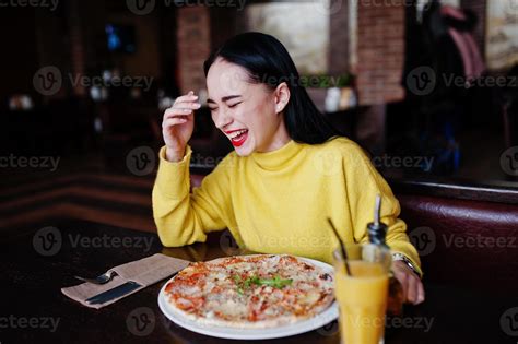 Funny Brunette Girl In Yellow Sweater Eating Pizza At Restaurant