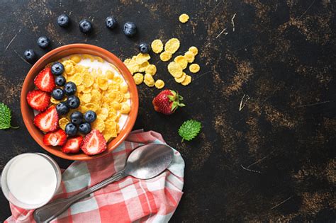 옥수수 우유와 딸기 어두운 소박한 배경에 식이 아침 식사 건강 한 식 생활의 개념입니다 보기 상위 공간을 복사 합니다 평면 배치