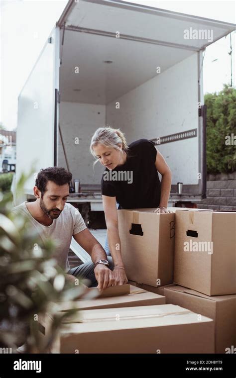 Male And Female Partners Unloading Cardboard Boxes During Relocation Stock Photo Alamy