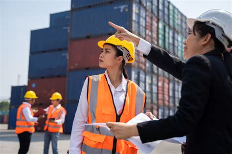 Foreman과 함께 일하는 여성 노동자 선적을 통제하고 조선소 또는 항구에서 수입 및 수출을 위해화물화물 선박에서 컨테이너의