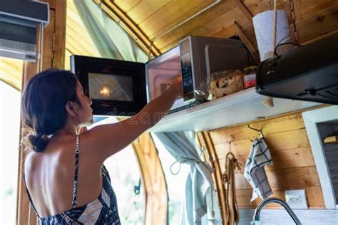 Latina Woman Cooking A Quick Meal In A Microwave Oven In A Country