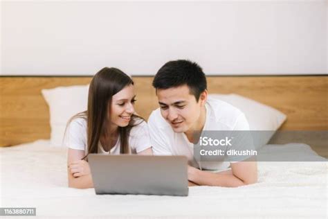 젊은 부부는 노트북과 침대에서 휴식 밝은 침실에 함께 누워 2명에 대한 스톡 사진 및 기타 이미지 2명 가정 생활 가족