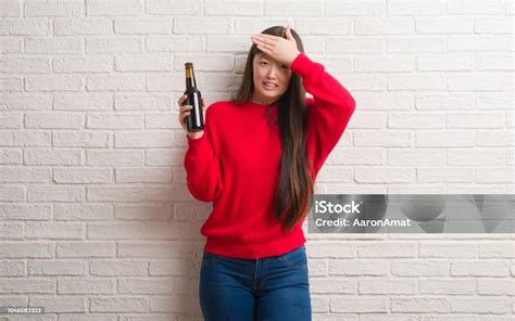 벽돌 벽 머리에 손으로 압박 하는 맥주를 마시는 동안 젊은 중국 여자는 수치심과 깜짝 얼굴로 충격 분노와 좌절 두려워 하 고
