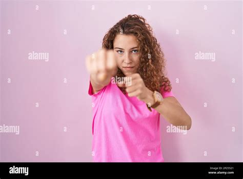 Young Caucasian Woman Standing Over Pink Background Punching Fist To