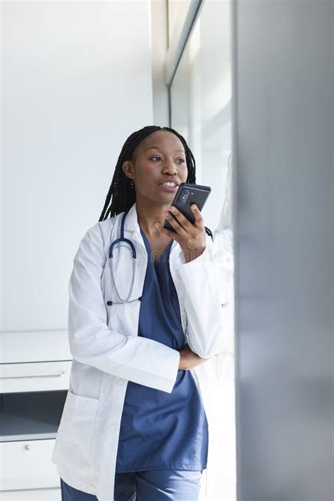 African American Female Doctor Wearing Lab Coat Using Tablet In