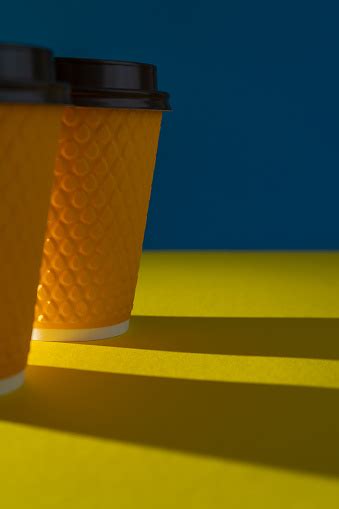 패스트 푸드 레스토랑에서 테이크 아웃 음료를위한 플라스틱 뚜껑이있는 노란색 갈비뼈 종이 컵 길거리 카페에서 커피 한 잔 코코아 차 텍스트에 배치합니다 파란색 배경 종이