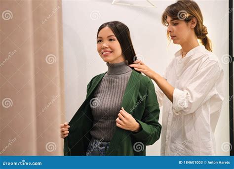 Young Fashion Consultant Helping Trying On Cardigan To Pretty Positive