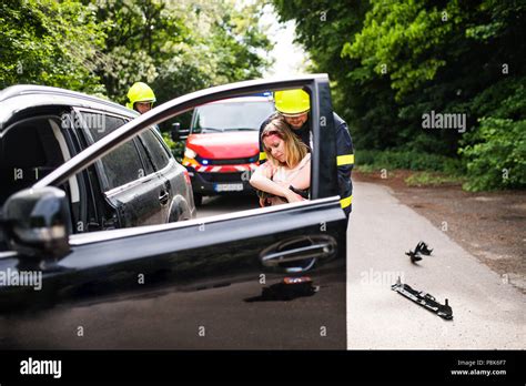 Two Firefighters Getting A Young Injured Woman Out Of The Car After An