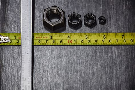 노란색 측정 테이프는 강판 질감이 있는 회색 검은 색 패턴 버니어 캘리퍼 엄선된 볼트 나사 크고 작은 크기의 크기를 측정합니다