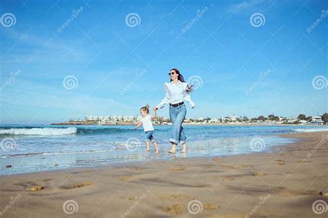 Madre E Hija Cogiendo La Mano Corriendo Descalzo Sobre La Arena Mojada