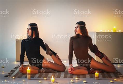 두 젊은 여자 하 고 아늑한 객실 내 양 초 무늬에 요가 아사 나 Eka의 Rajakapotasana 2명에 대한 스톡 사진 및