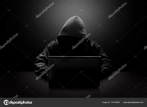 Hooded Computer Hacker Stealing Information With Laptop Stock Photo