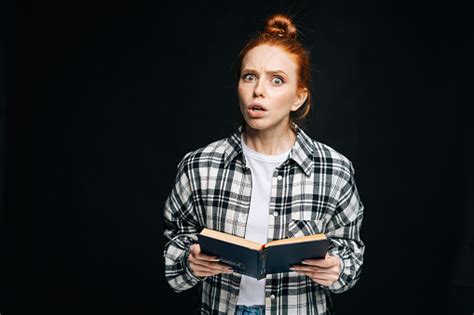 충격을 받은 젊은 여성 대학생 과 함께 열린 입 들고 책을 들고 카메라를 보고 검은색에 대한 스톡 사진 및 기타 이미지 검은