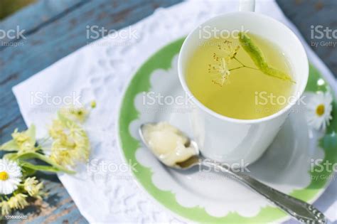 린든꽃은 파란색 나무 배경에 꿀을 얹은 녹색 장식 접시와 흰색 장식 접시가있는 흰색 컵에 차를 꽃 흰색 꽃이있는 빈티지 배경에