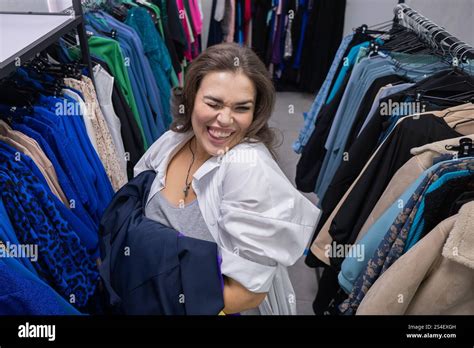 Top View Of A Chubby Cheeked Woman Holding An Armful Of Clothes In A