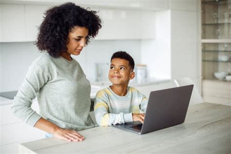 A Young Mother Helps Her Son With His Homework The Boy Looks At The