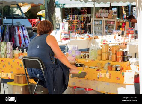 Female French Market Trader Sitting On Stool Waiting For Customers