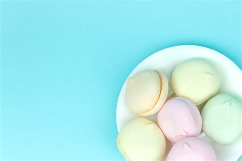 달콤하고 통풍이 좋은 부드러운 파스텔과 흰색 마시멜로는 파스텔 배경에 접시에 누워 있는 마카롱처럼 보입니다 구멍이 많은에 대한