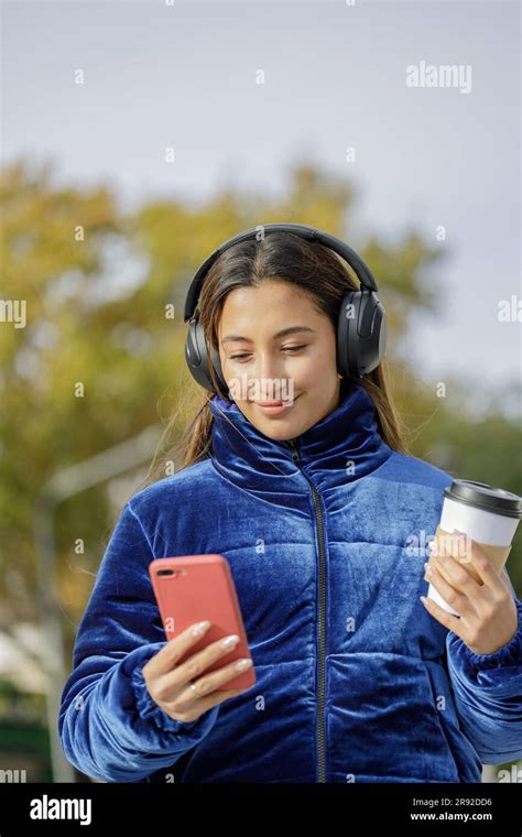 Latin Girl With Headphones And A Disposable Cup Of Coffee Looking At