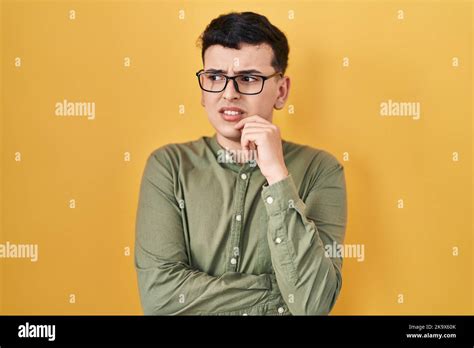 Non Binary Person Standing Over Yellow Background Looking Stressed And Nervous With Hands On
