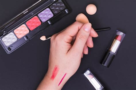 Marcas De Batom Na Mão Da Fêmea Com Produtos Cosméticos Em Fundo Preto