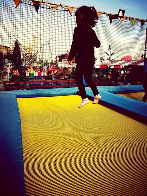 Premium Photo Girl Jumping On Trampoline Against Sky