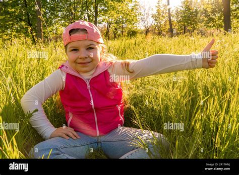 Une Jeune Fille Gaie Est Assise Dans Lherbe Verte épaisse Et Fait Un