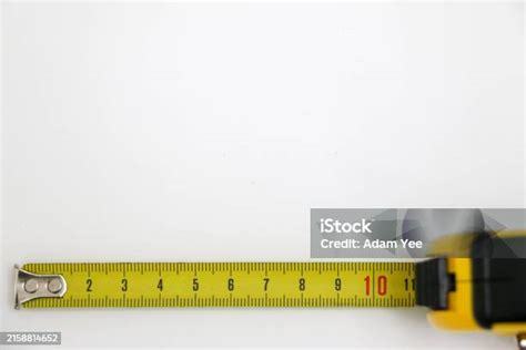 흰색 배경 하단에 최대 10cm까지 측정되는 검은색과 노란색 개폐식 줄자로 길이 너비 높이 개념 정확도 및 정밀도를 측정합니다