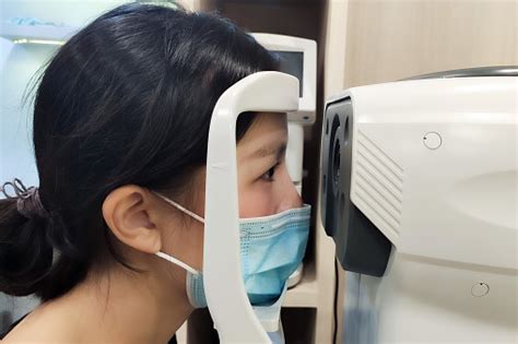 안경사 사무실에서 시력 환자를 검사하는 외과 마스크와 검안사를 가진 아시아 여성 안과의사에 대한 스톡 사진 및 기타 이미지