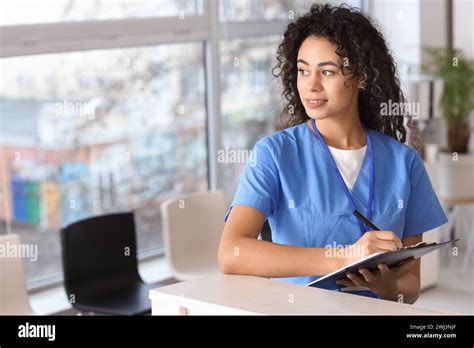 Female African American Medical Intern Writing In Clipboard At Hospital