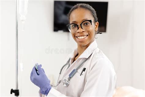 Female Doctor In White Coat And Blue Gloves Holds A Syringe With An