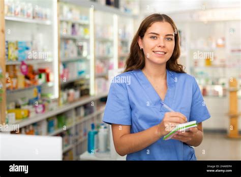 Young Smiling Female Pharmacist Making Important Notes In A Notebook