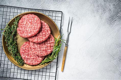 로즈마리와 백리향이 있는 강판에 향신료를 곁들인 생 다진 쇠고기 버거 흰색 배경입니다 평면도 복사 공간 0명에 대한 스톡 사진