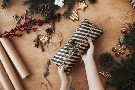 소박한 크리스마스 선물 플랫 레이를 포장 세련된 줄무늬 종이와 소나무 가지 콘 진저 브레드 쿠키 스레드 시골 나무 테이블에 계피에 크리스마스 선물을 포장 손 12월에 대한