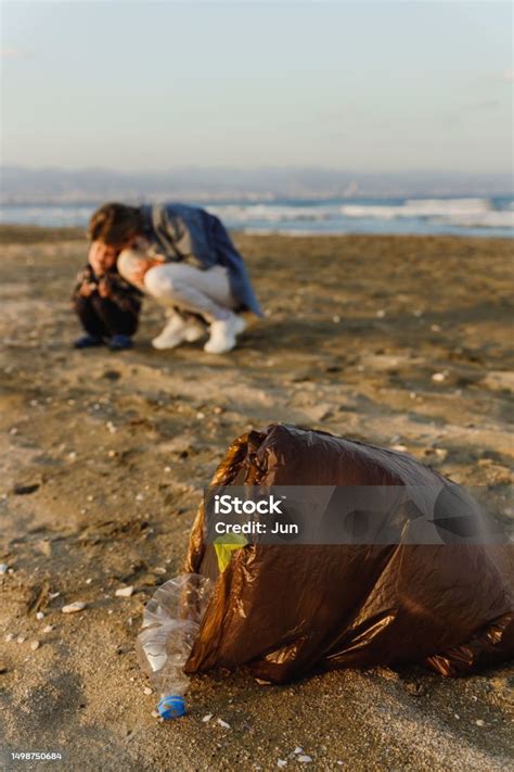 백인 가족은 해변에서 플라스틱 쓰레기를 수거하고 있다 어머니는 아들에게 자연을 깨끗하게 유지하는 것을 가르치고 있습니다 병이 든 비닐 봉지에 집중 18 23 개월에 대한