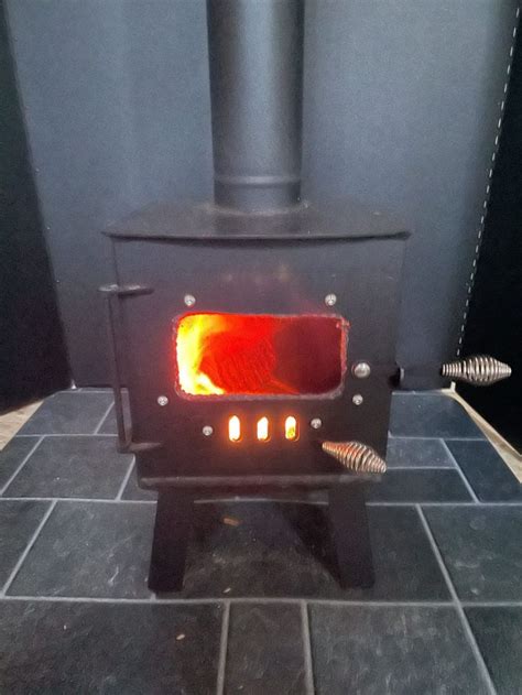 A Black Stove Sitting On Top Of A Tile Floor Next To A Wall With A Red