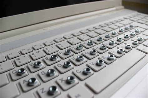 Angled Side View Of A Computer Keyboard With An Iron Nut On Each Button