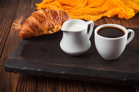 갓 구운 크루아상 잼 갈색 나무 배경에 흰색 컵에 커피 한잔 프랑스어 아침 식사 아침에 신선한 빵 현대 어두운 분위기 스타일입니다 맛 있는 디저트 가로 배너 갈색에 대한