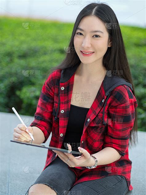 女大学生坐在公园里用手写笔玩电子平板电脑