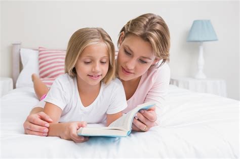 Mãe E Filha Lendo Livro Juntos Na Cama Foto Premium