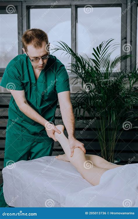 A Male Massage Therapist Massages The Feet And Legs Of Female Legs