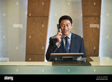 Portrait Of Smiling Vietnamese Receptionist Calling On The Phone Stock