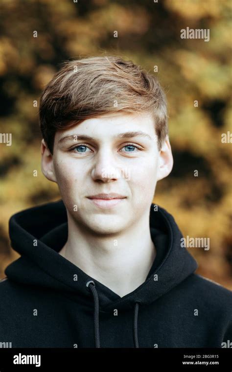 Portrait Of A Smiling Teenage Boy Standing Outdoors In Autumn